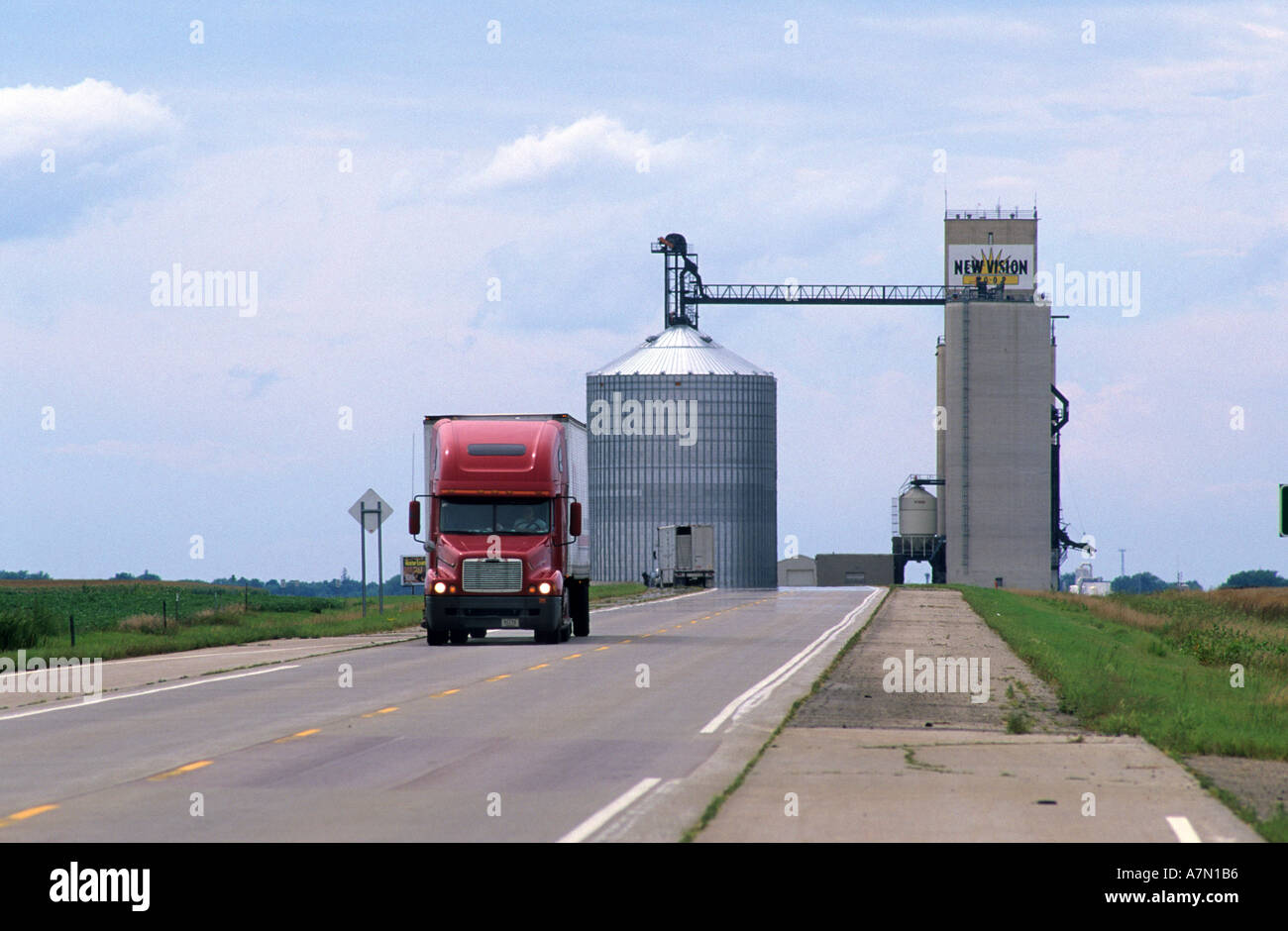 A grain elevator and storage bin and truck traveling on the highway in ...
