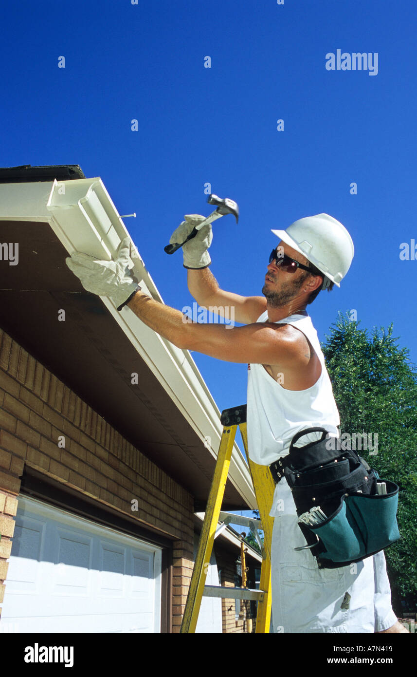 Worker putting on gutters and downspouts on a house Stock Photo - Alamy