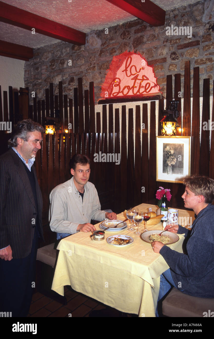 Owner chats with diners as they eat pasta in an Italian restaurant in ...