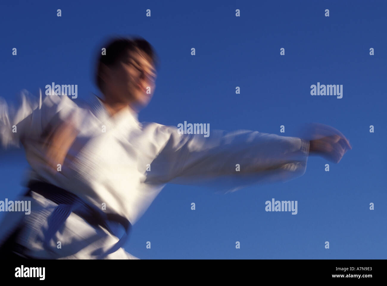 Blurred action shot looking up at a martial artist in action outdoors ...