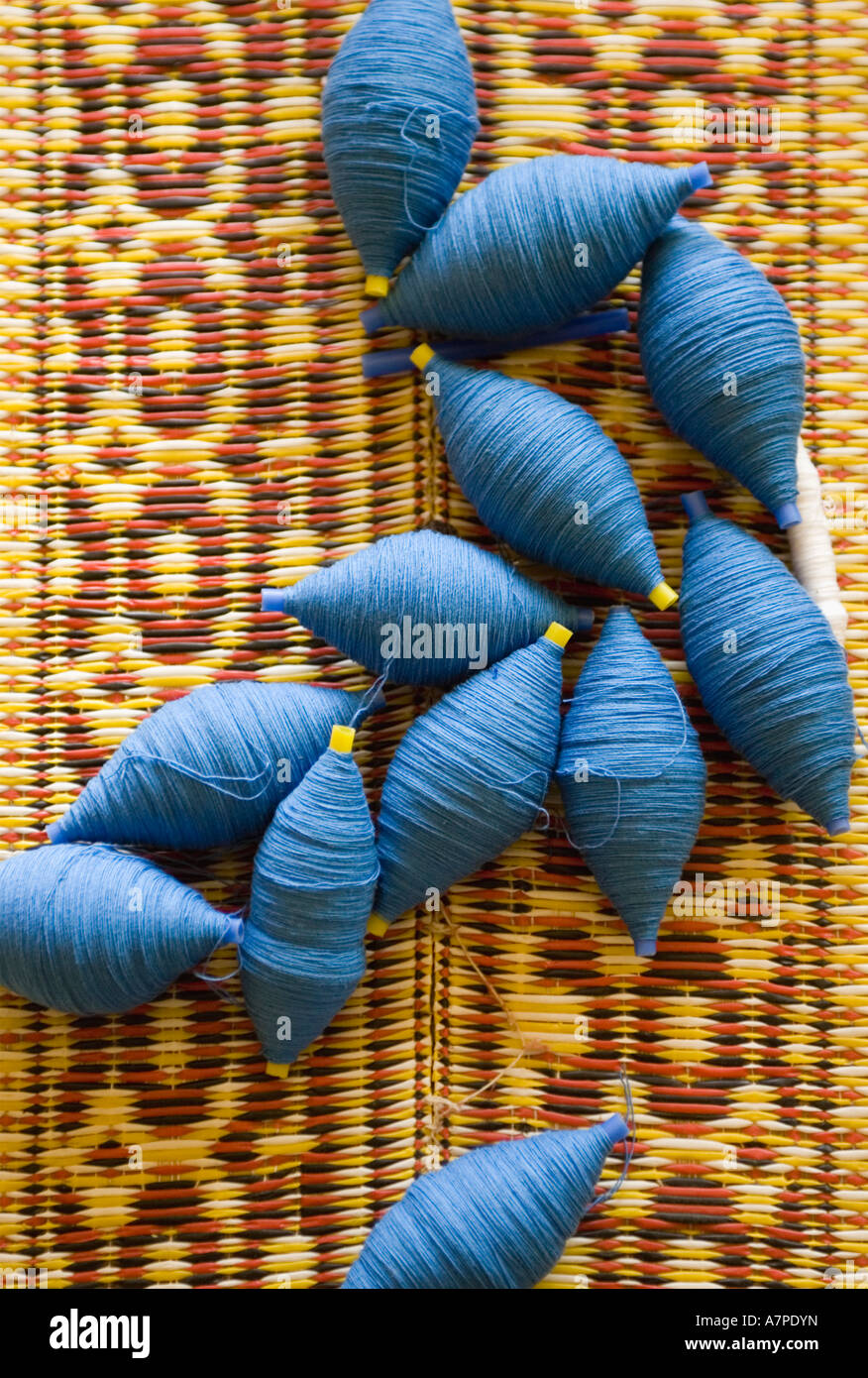Bobbins of blue thread await placement in a traditional loom in ...