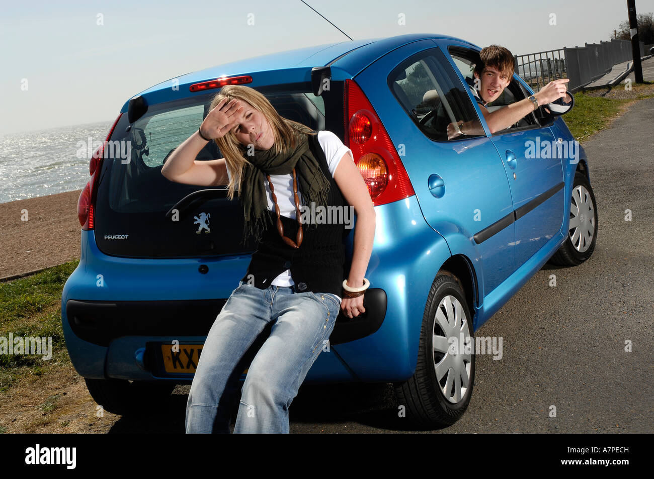 Young woman push starting a car while the man shouts encouragement ...