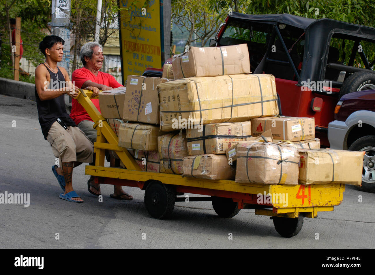 Two men pulling a trolly Stock Photo - Alamy