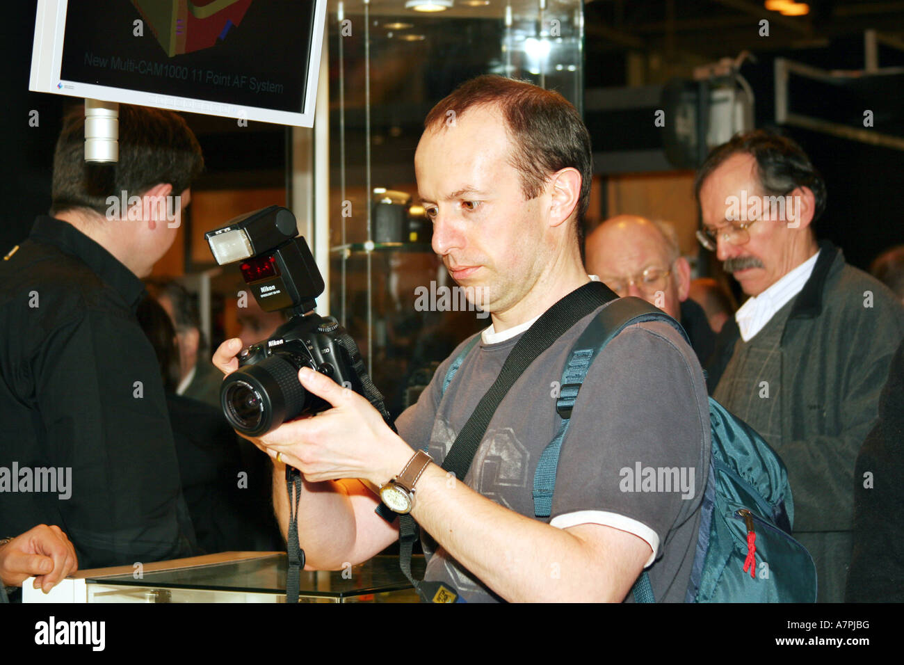 Man looking at digital Single Lens Reflex camera with flash attached ...