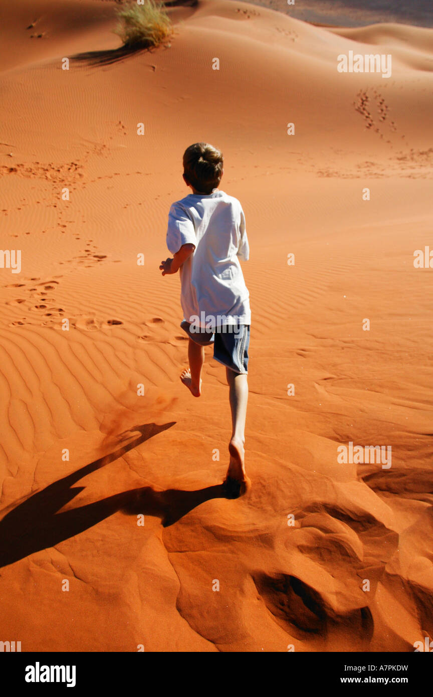 A bare footed boy running down a red Namib desert sand dune Namibrand ...