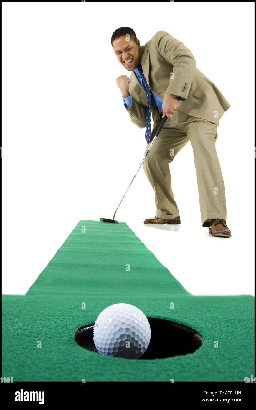 Man in suit with putter and golf ball in hole Stock Photo - Alamy