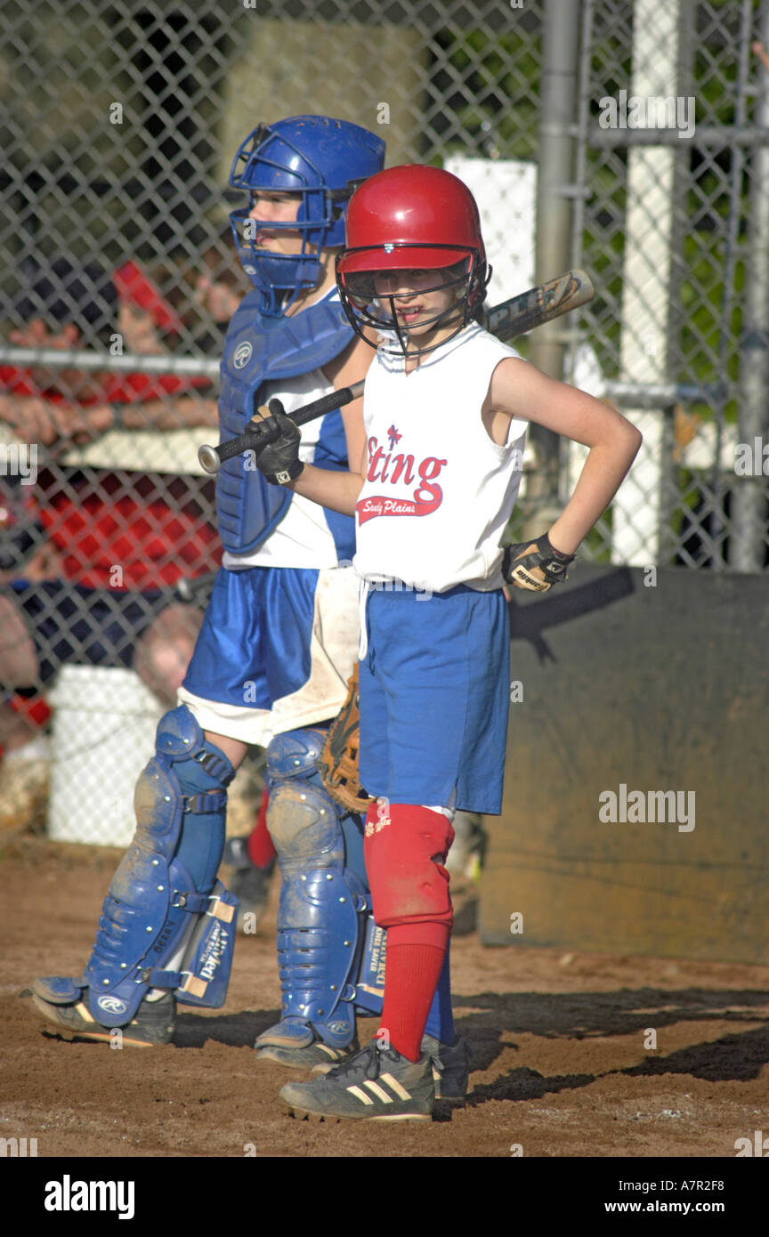 Girls learning to hit softball with coaches and practice net in ...