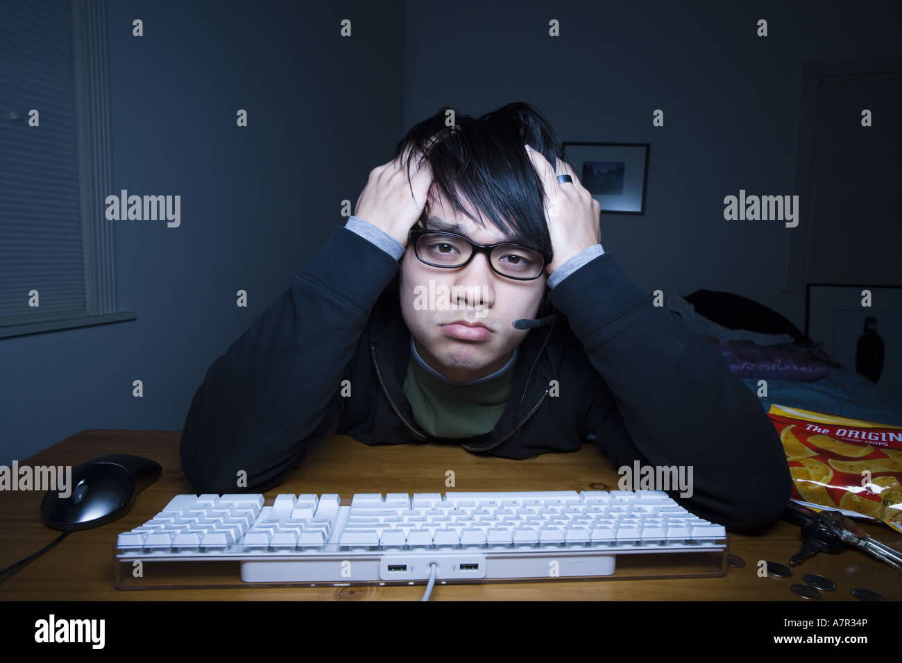 Man at keyboard with headset and hands on head pouting Stock Photo - Alamy