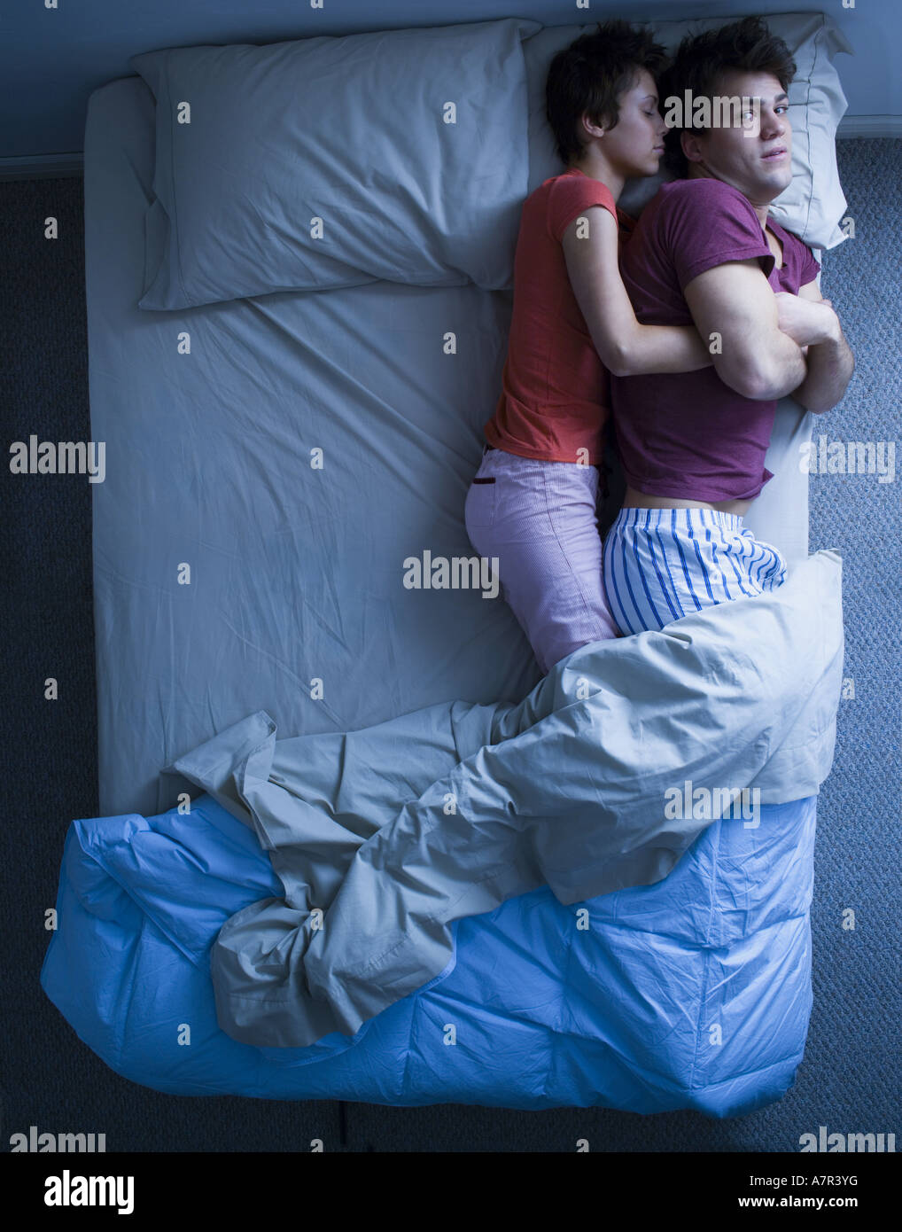 Sleeping woman snuggling awake man in bed Stock Photo - Alamy