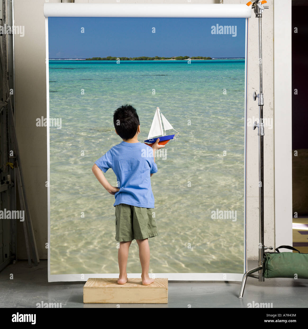 Boy with toy boat looking at ocean rear view Stock Photo - Alamy