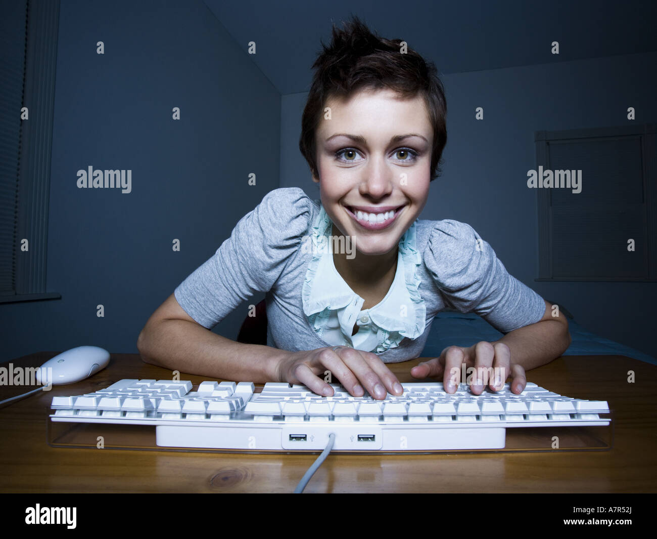 Woman sitting at keyboard typing and smiling Stock Photo - Alamy