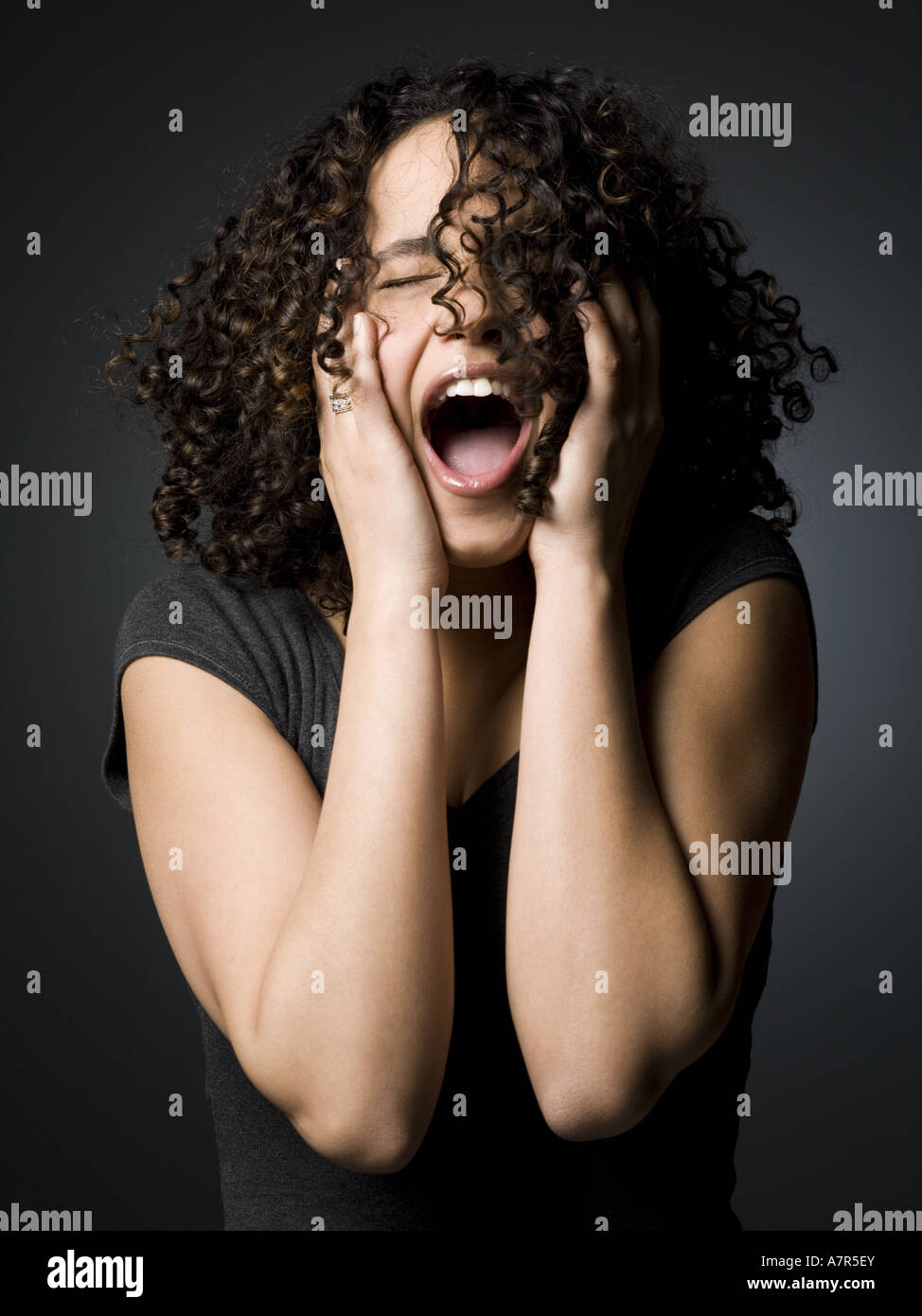 Woman with mouth open and closed eyes with hands on face Stock Photo ...