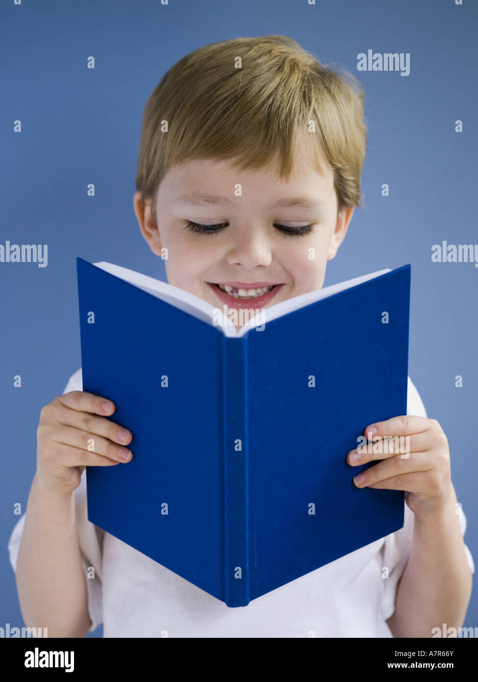 Boy reading book and smiling Stock Photo - Alamy