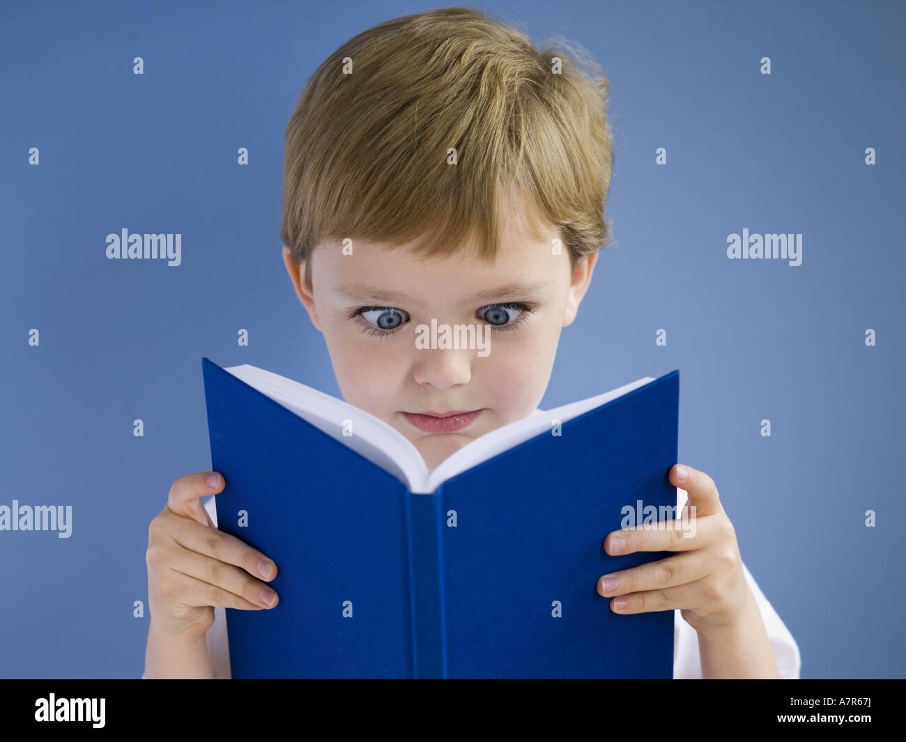 Boy reading harcover book cross eyed Stock Photo - Alamy