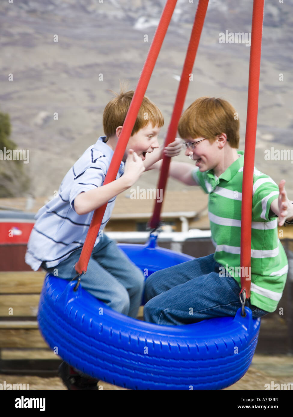 Two boys playing on tire swing outdoors Stock Photo - Alamy