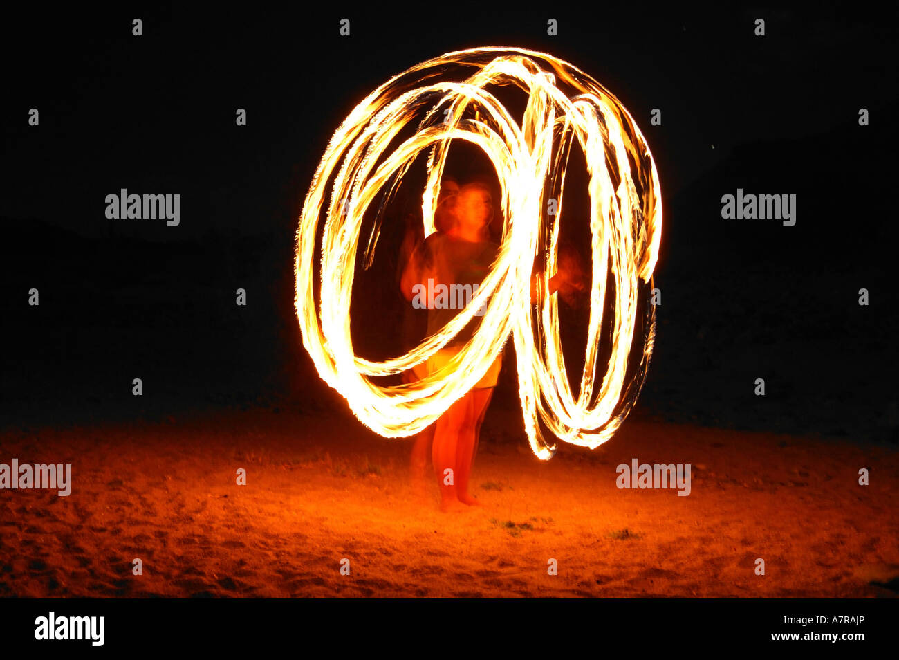 A long exposure photograph of an entertainer swirling fire chains at ...