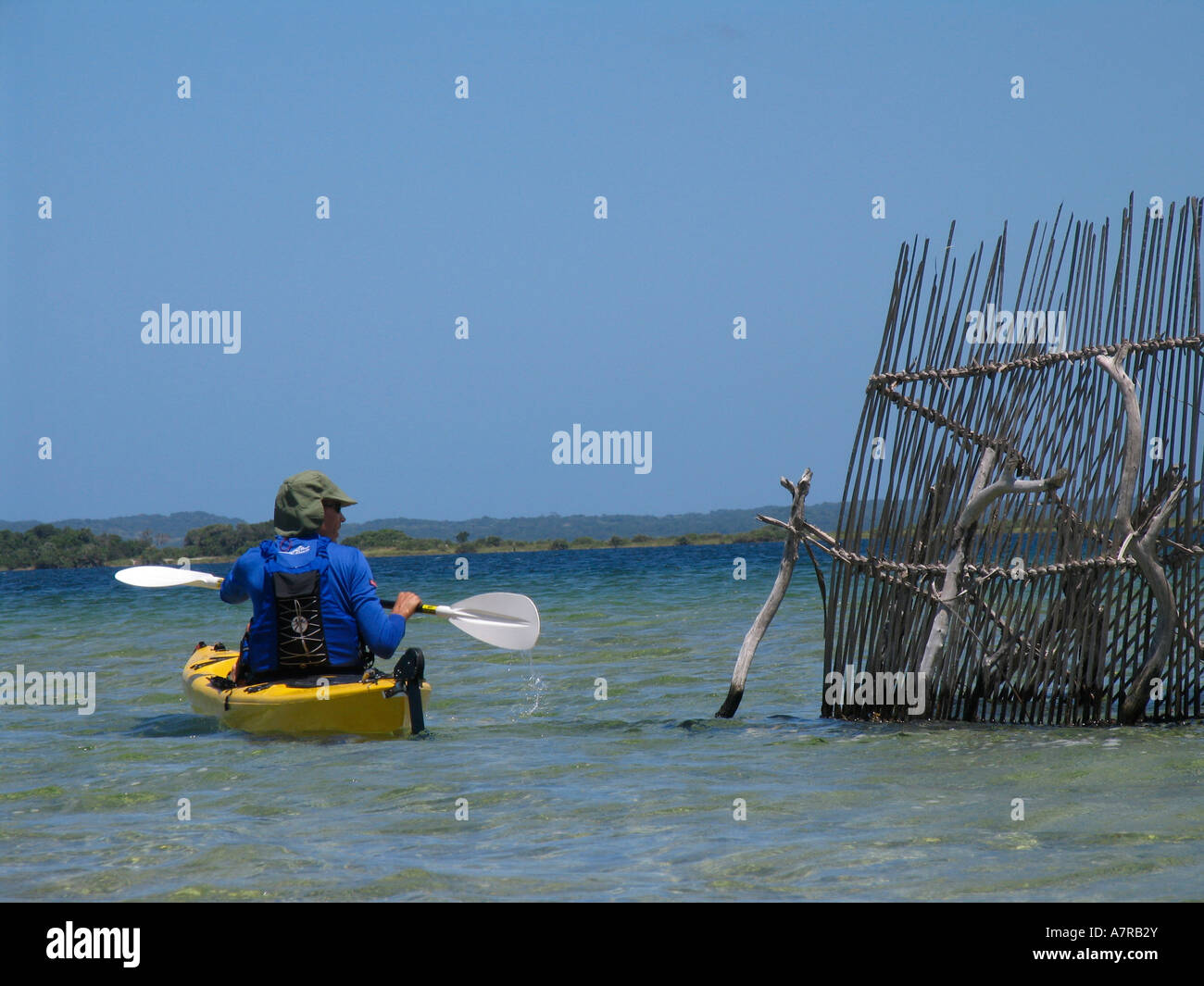 A man paddles past a fish kraal fish trap in the Kosibay estuary ...