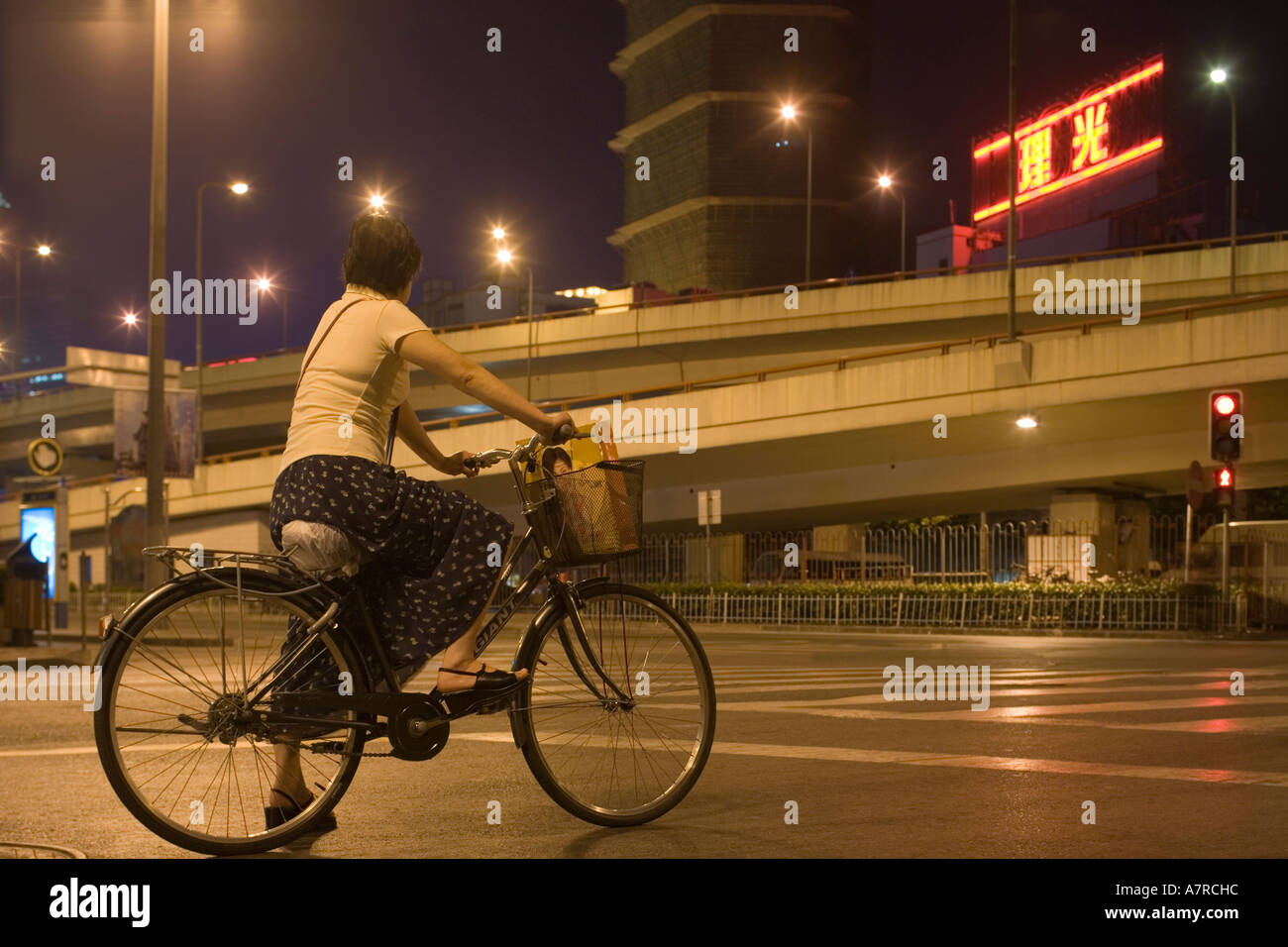 Asia China Shanghai Young Chinese woman on bicycle waits for light to ...