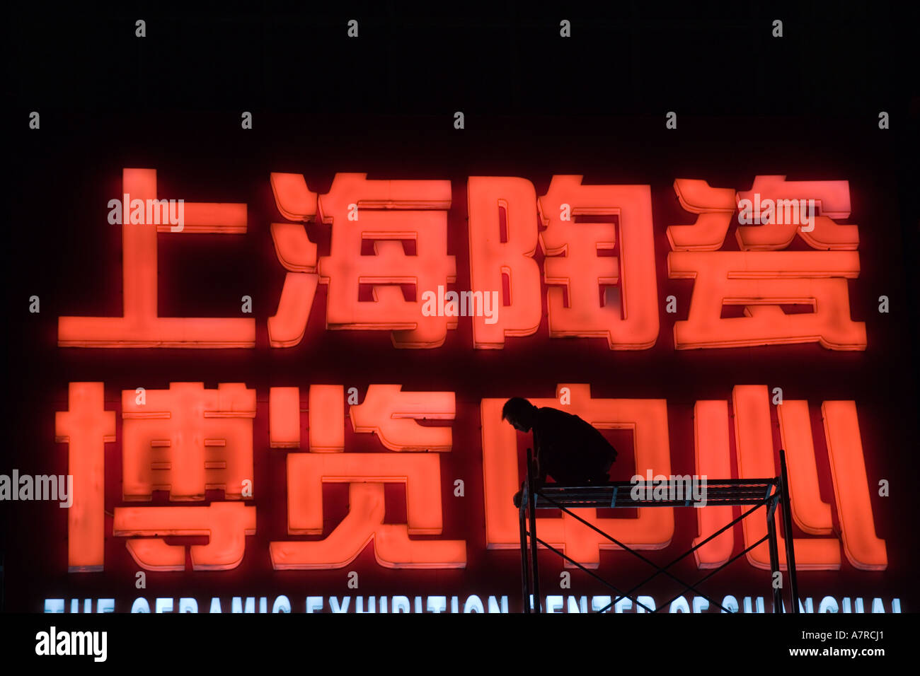 Asia China Shanghai Workmen on scaffolding are silhouetted by neon ...