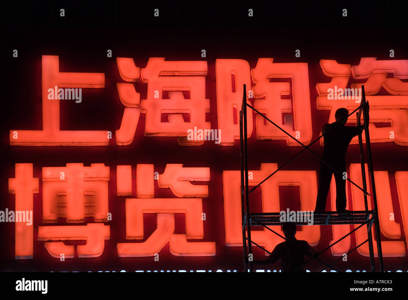 Asia China Shanghai Workmen on scaffolding are silhouetted by neon ...