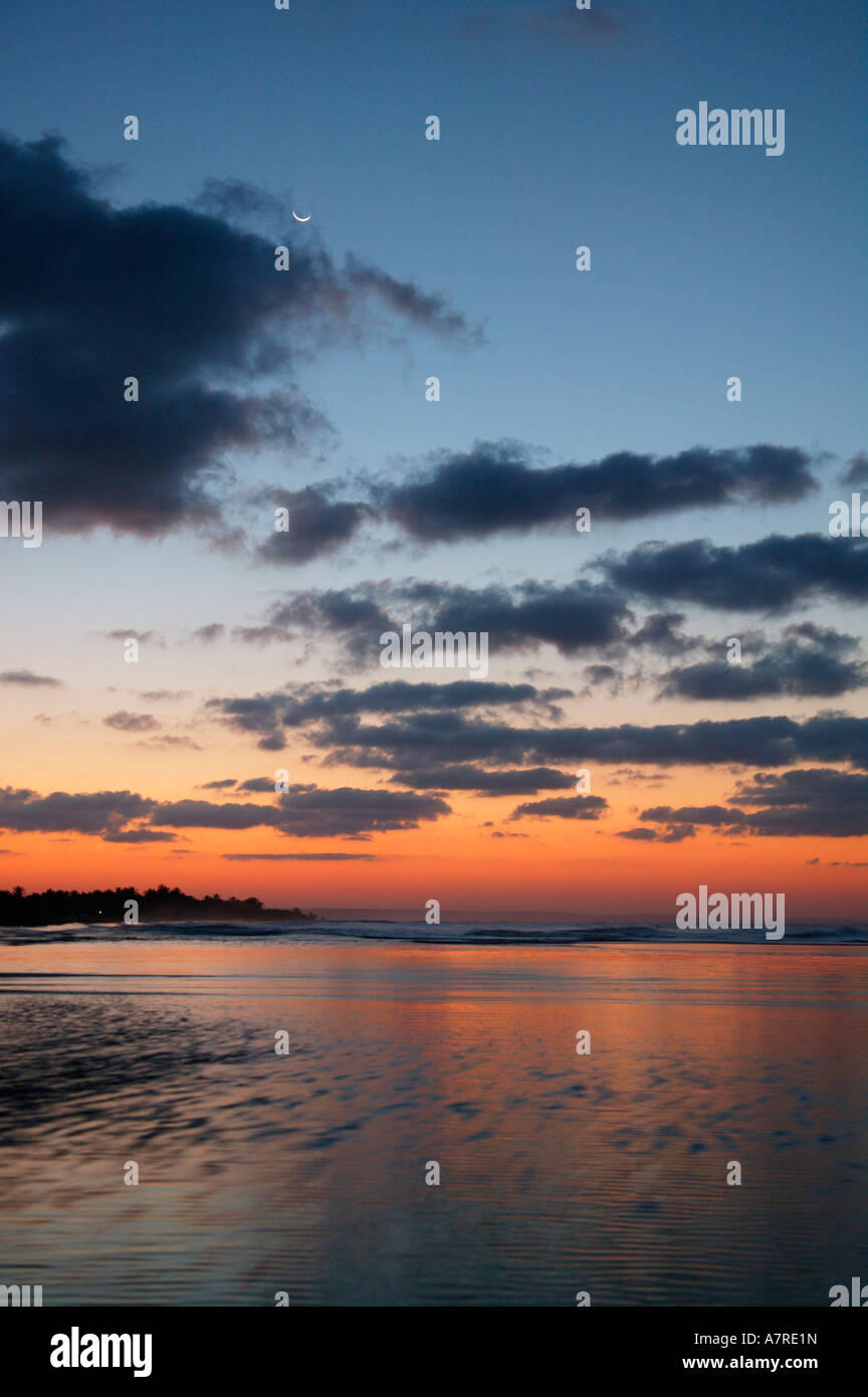 Moody beach sunset with a sickle moon in the sky Barra Inhambane ...