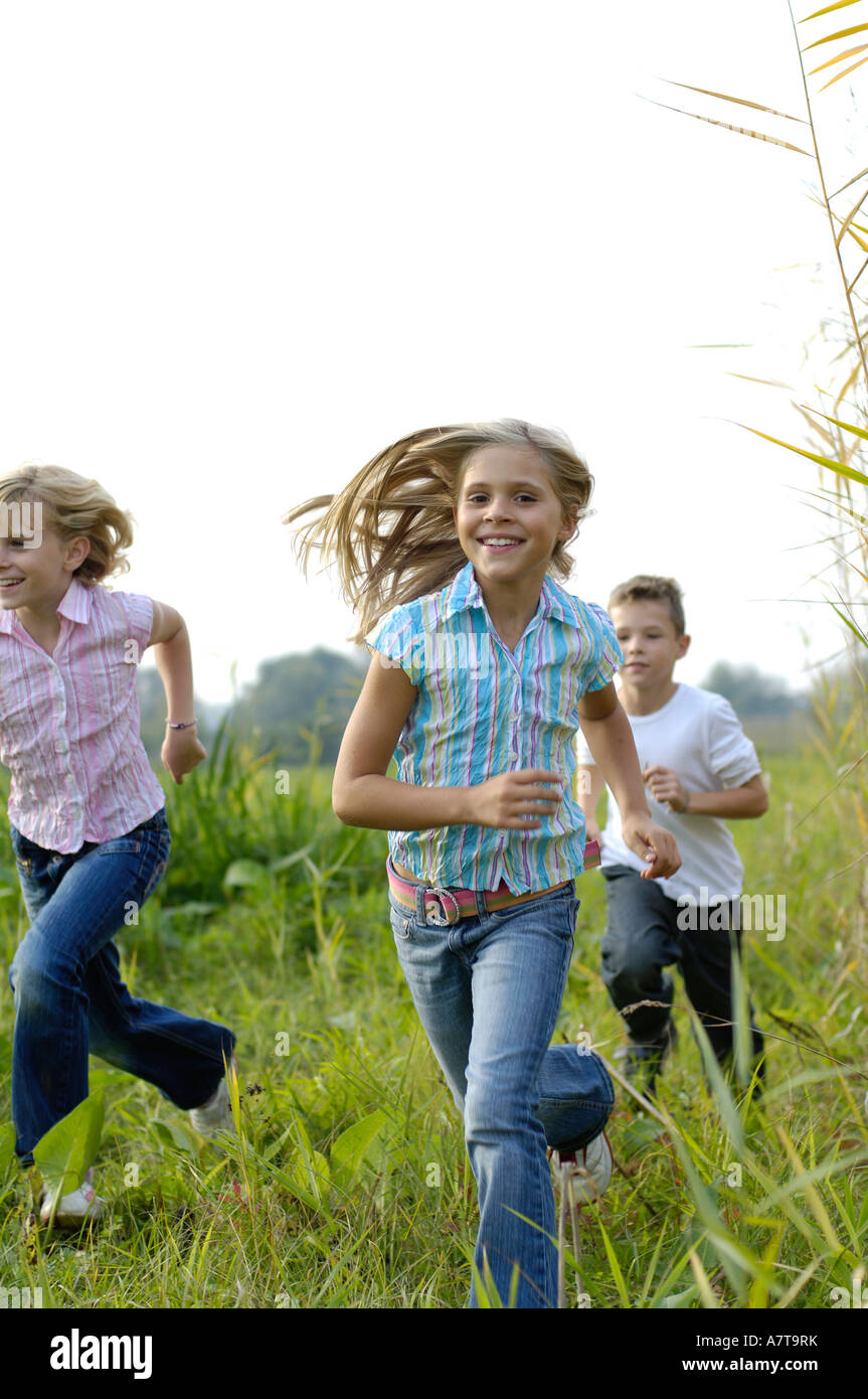 Brother and sisters running in field Stock Photo - Alamy