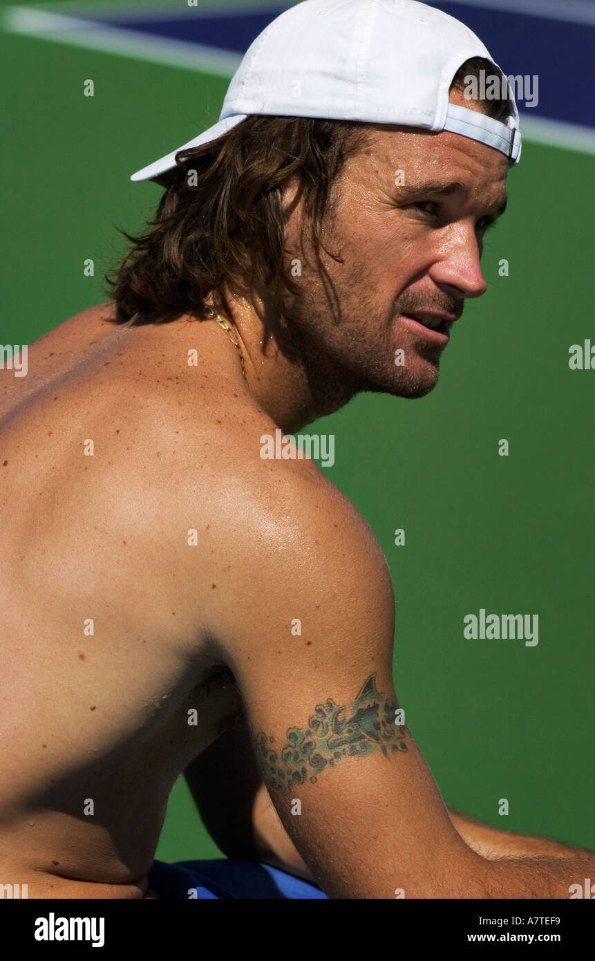 Tennis professional Carlos Moya rests after practicing at the 2004 ...