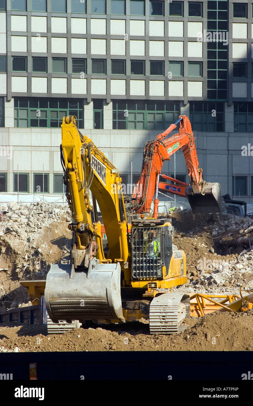 Two JCBs clearing rubble in front of office block Stock Photo - Alamy