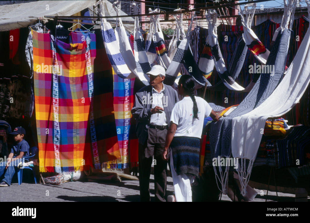 Male consumer with shopkeeper at street market stall Otavalo Imbabura ...