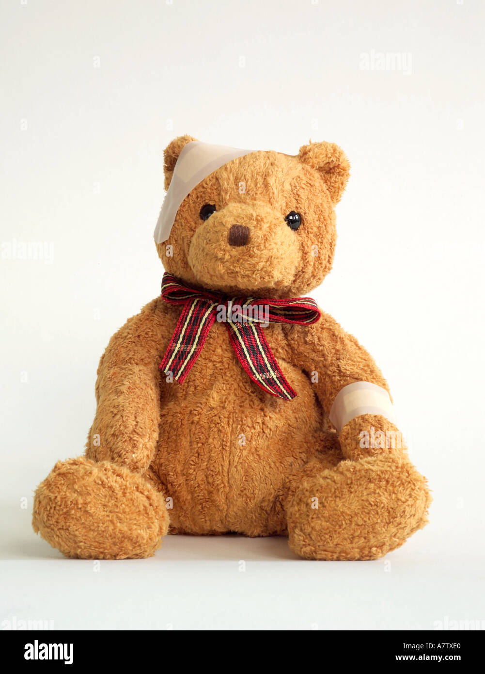 brown teddy bear with red check ribbon bow plaster on one arm and ...