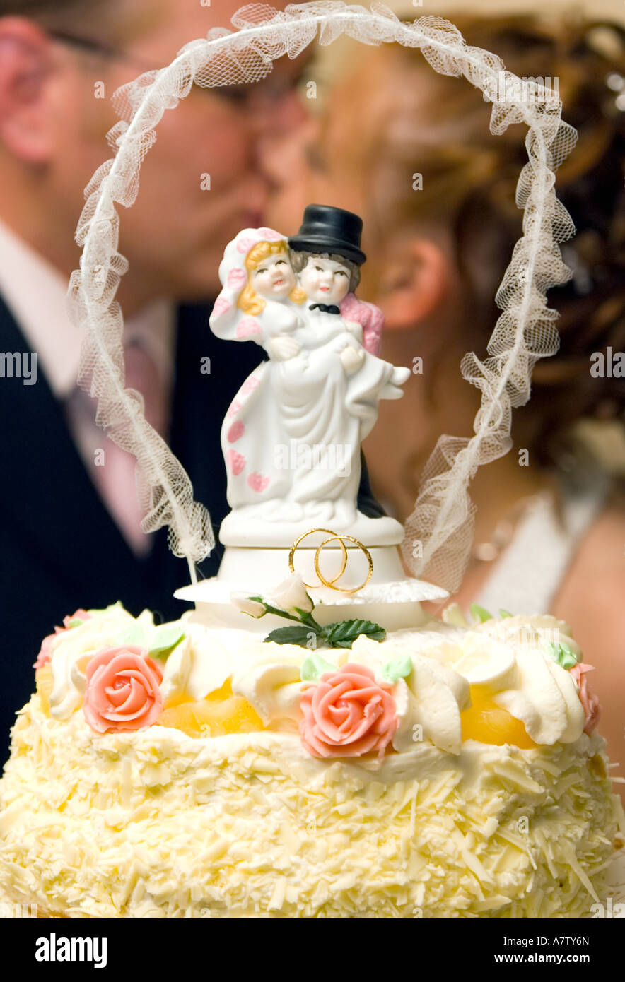 wedding cake with the newlyweds behind kissing blurred Stock Photo - Alamy