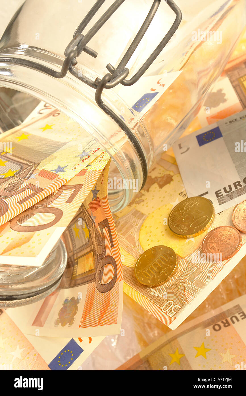 Money spilling out of glass jar Stock Photo - Alamy