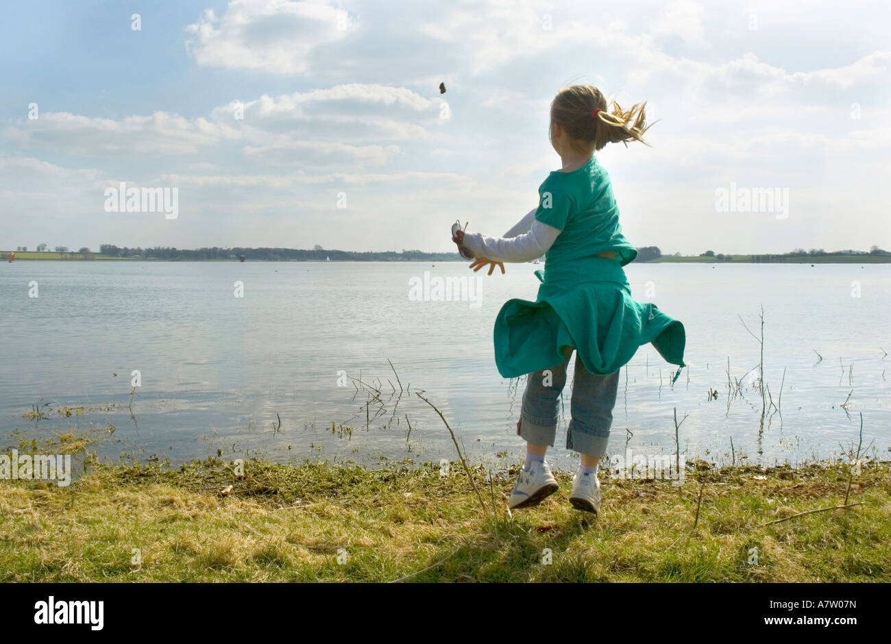 A Young girl throwing stone into Rutland Water Stock Photo - Alamy