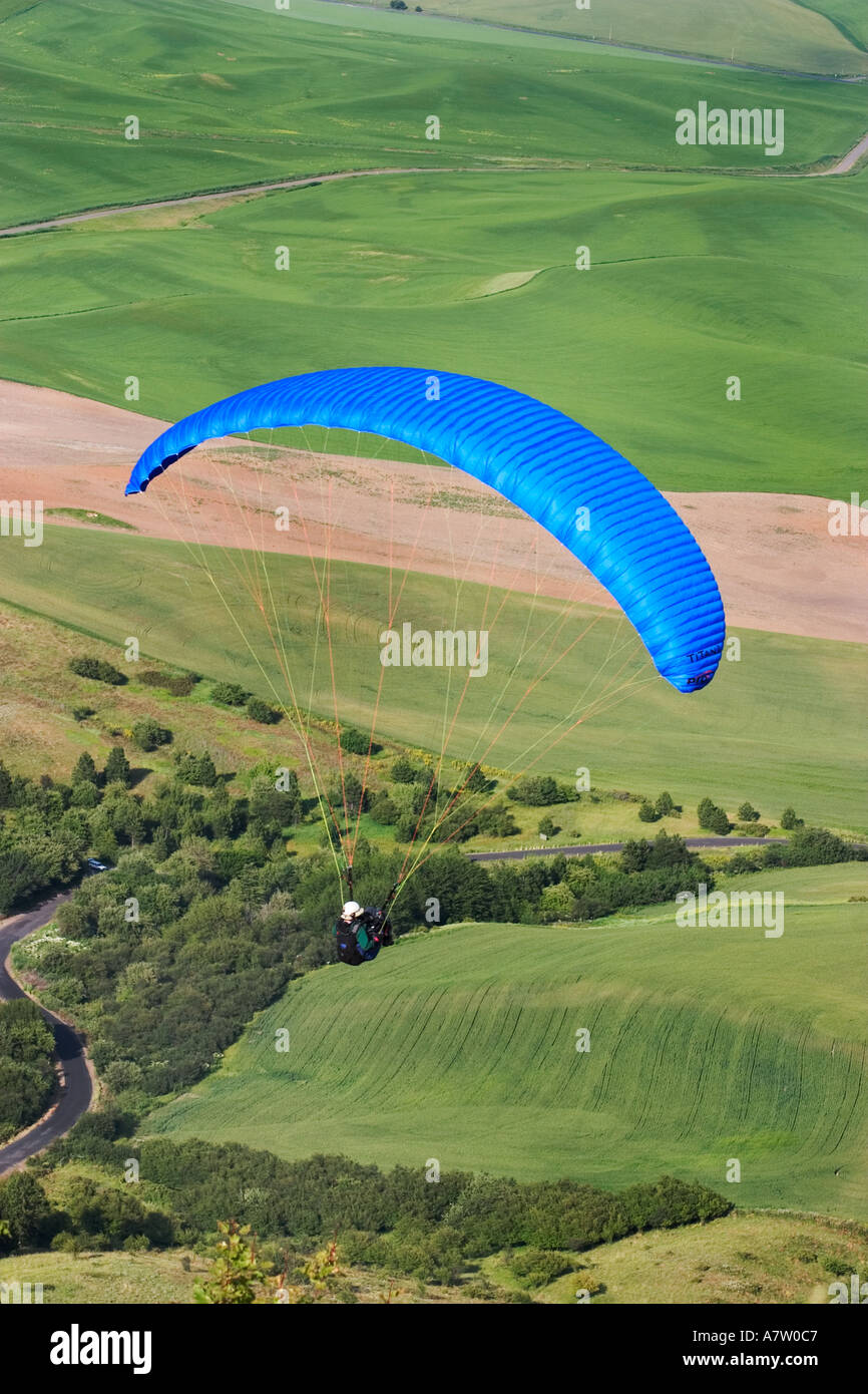 A paraglider rides thermal updrafts from green wheatfields in Eastern ...