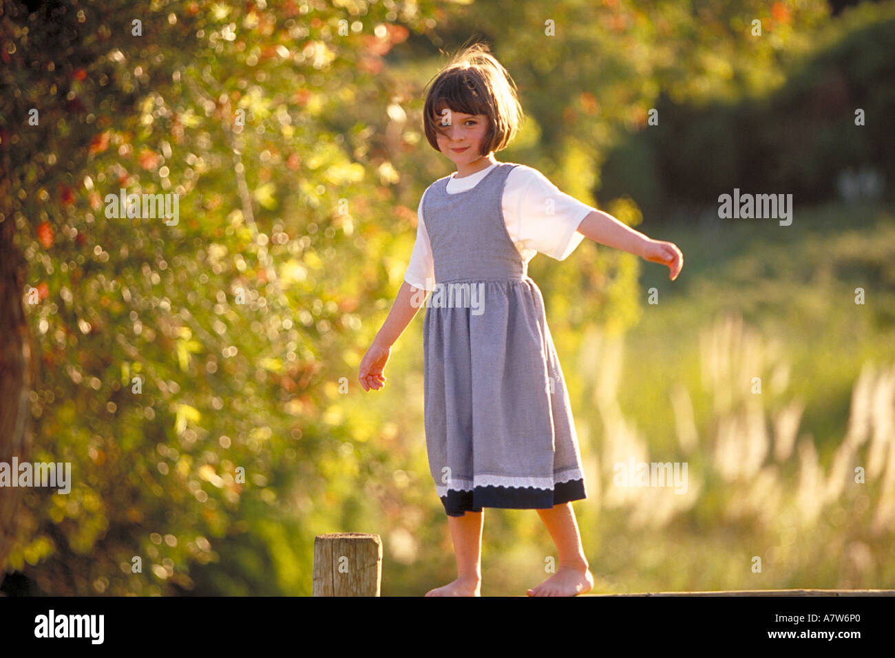 portrait of dark-haired 8-year-old girl balancing on a tree trunk Stock ...