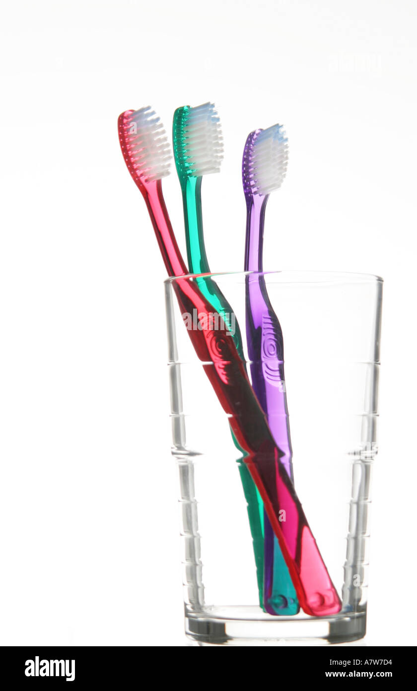 Clear coloured toothbrushes in a clear glass with a bright white ...