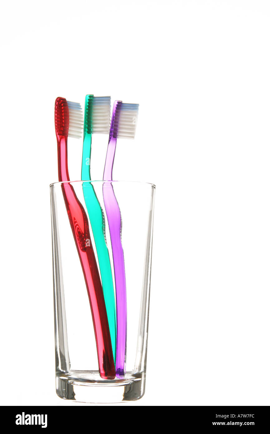 Clear coloured toothbrushes in a clear glass with a bright white ...