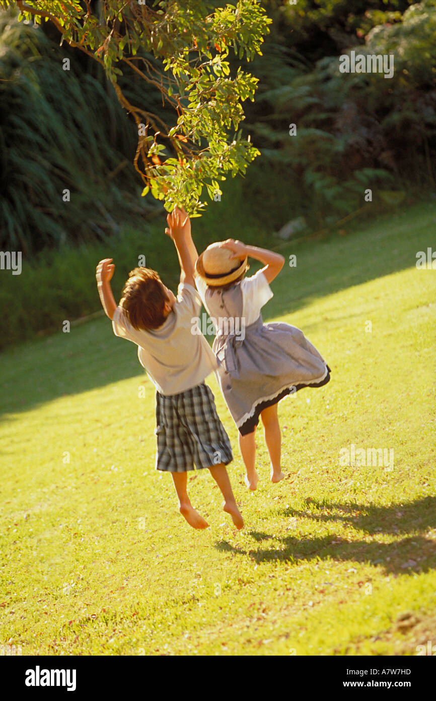 two kids jumping over a meadow Stock Photo - Alamy