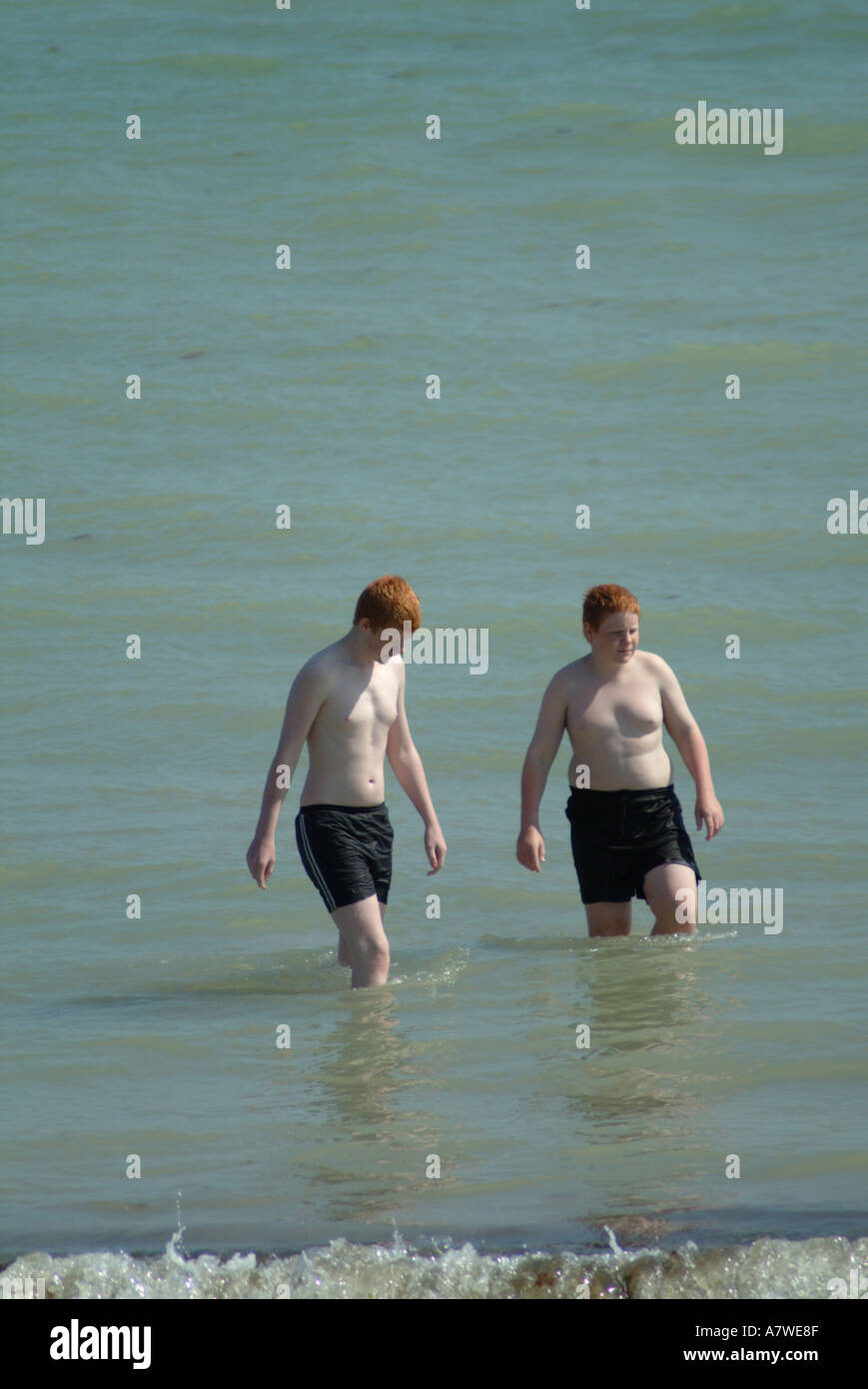 Two boys walk in the shallow water at Climping beach Stock Photo - Alamy