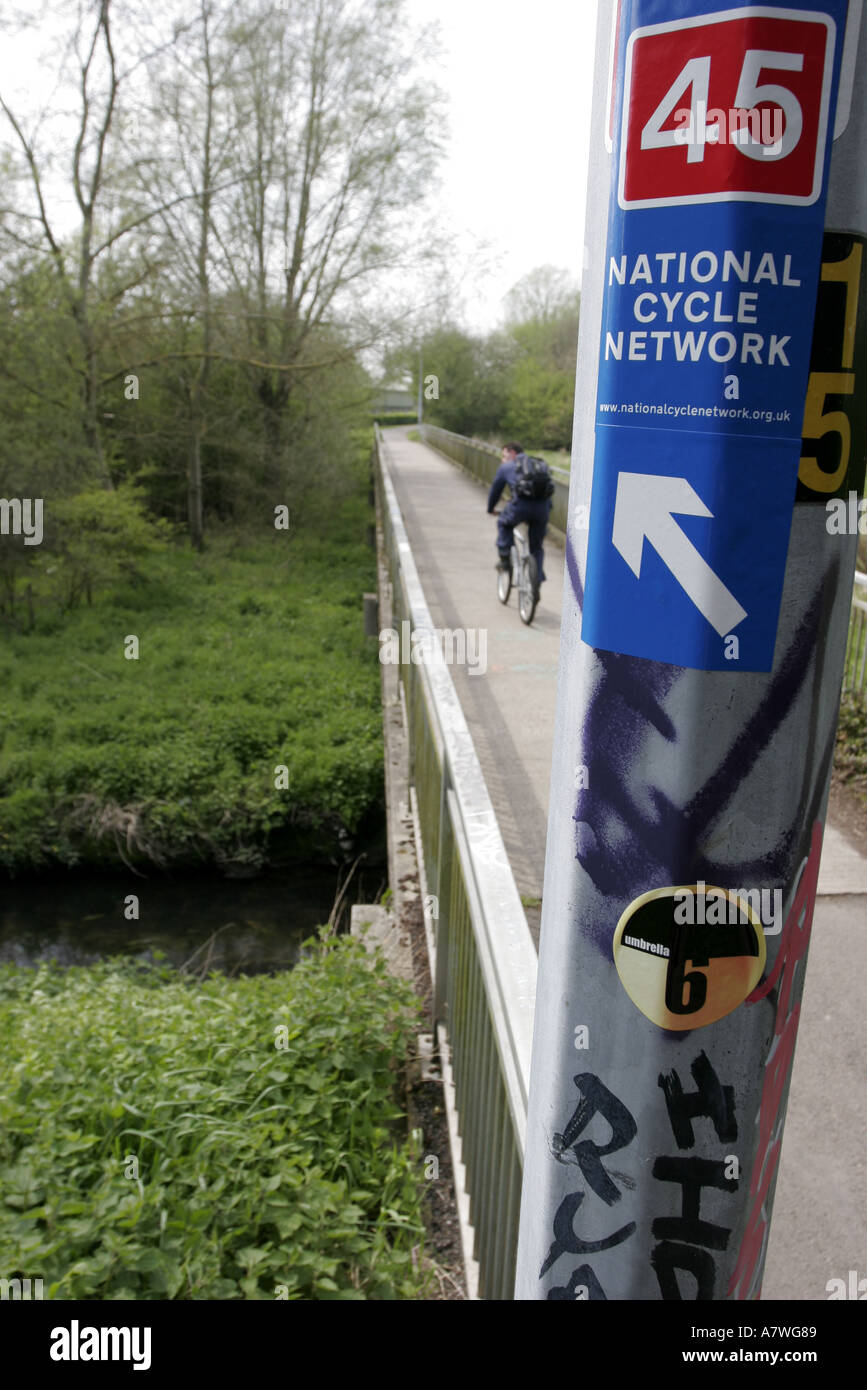 Cyclist on cycle path over bridge with national cycle path network sign ...