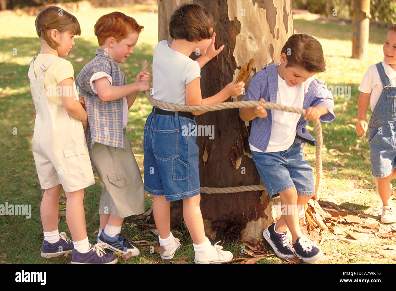 group of children binding a girl on a tree trunk Stock Photo - Alamy