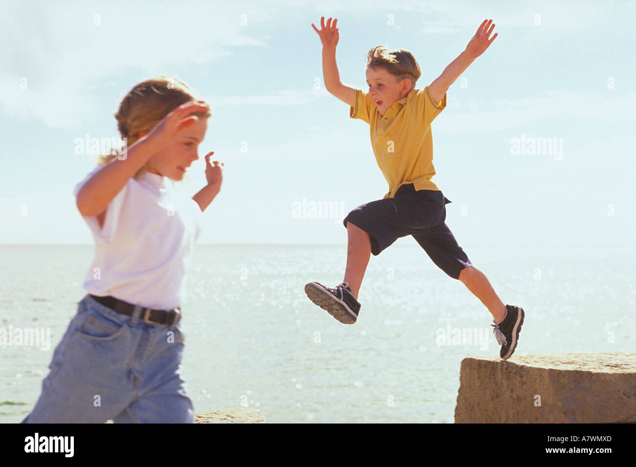 two boys jumping over rocks Stock Photo - Alamy