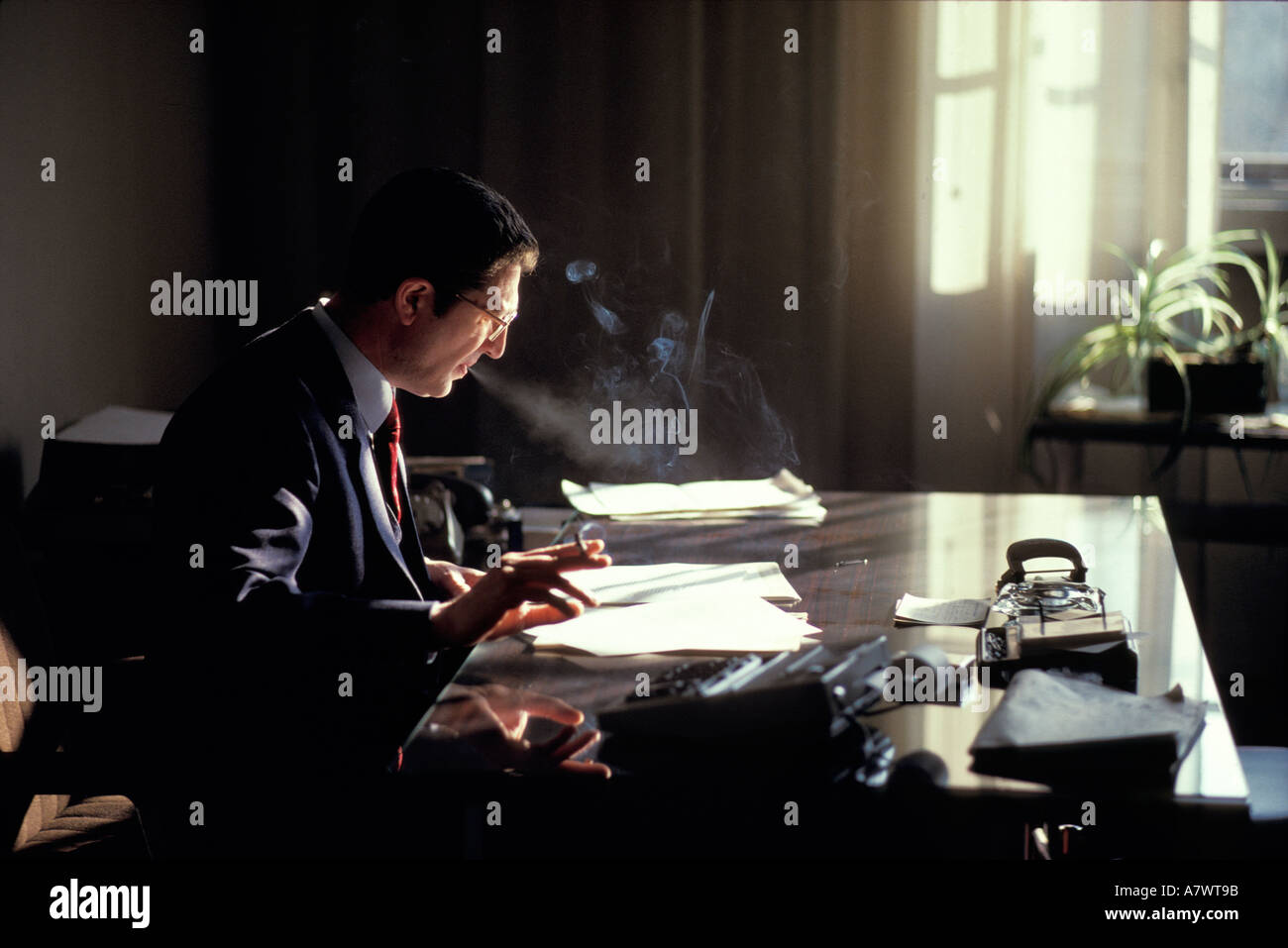 Italian businessman smoking at desk late afternoon sunlight window ...