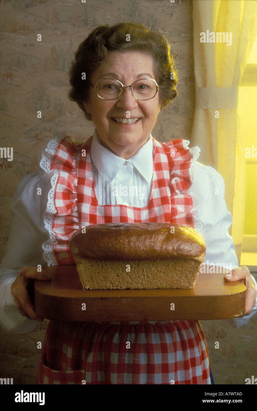 Fresh baked bread presented by smiling woman warm window light glasses ...