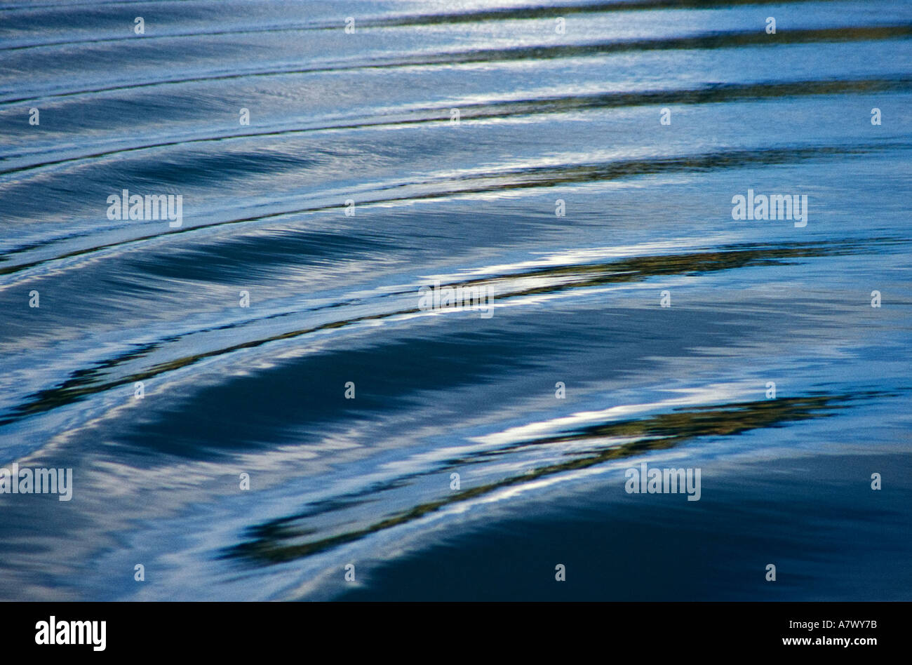 Wave patterns from boats wake on a tranquil silky calm water surface ...