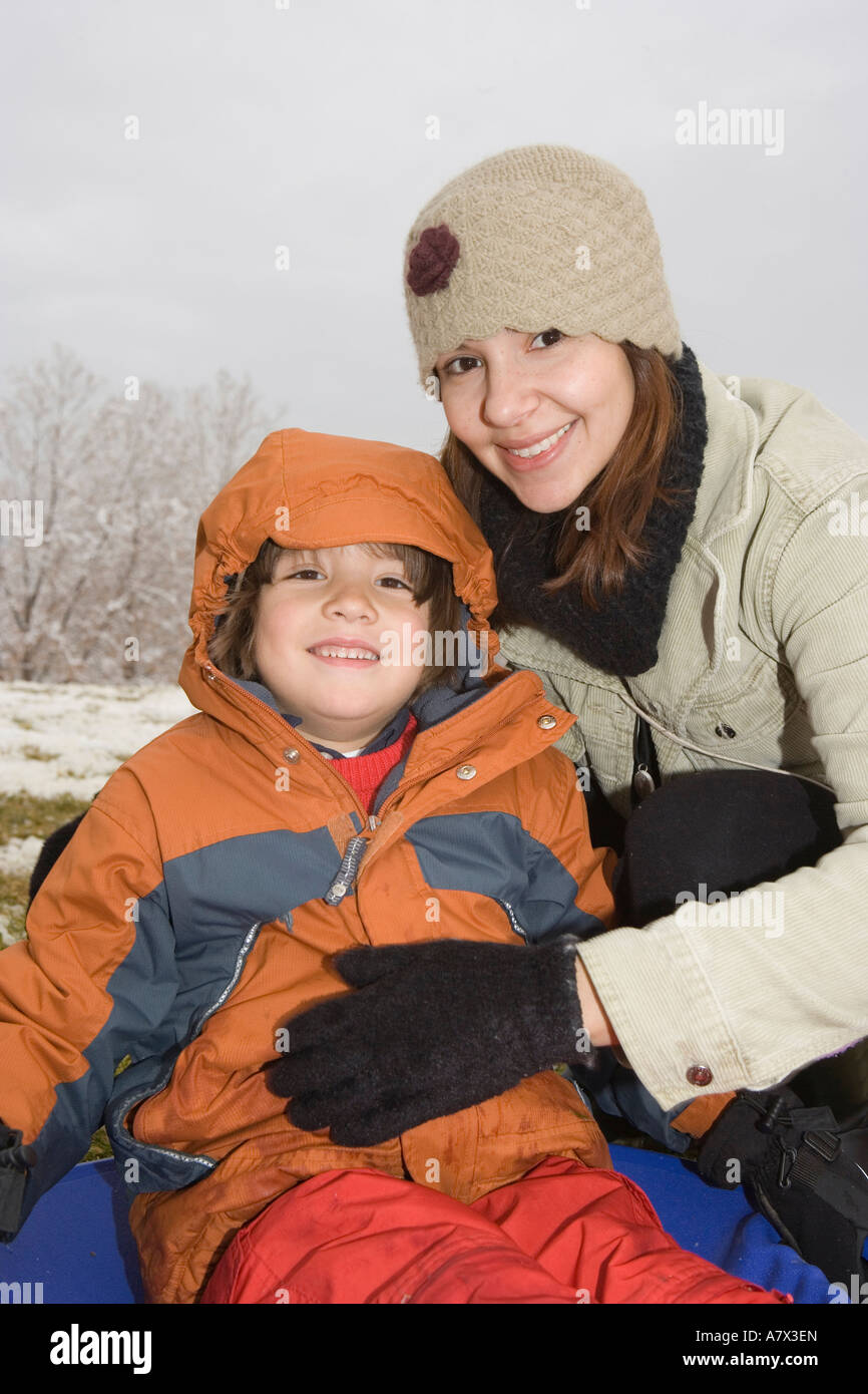 mother and seven year old son getting ready to go sledding in the snow ...