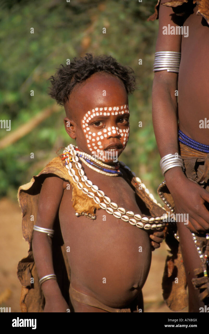 A small Hamar boy in shell-decorated garb and traditional facepaint ...