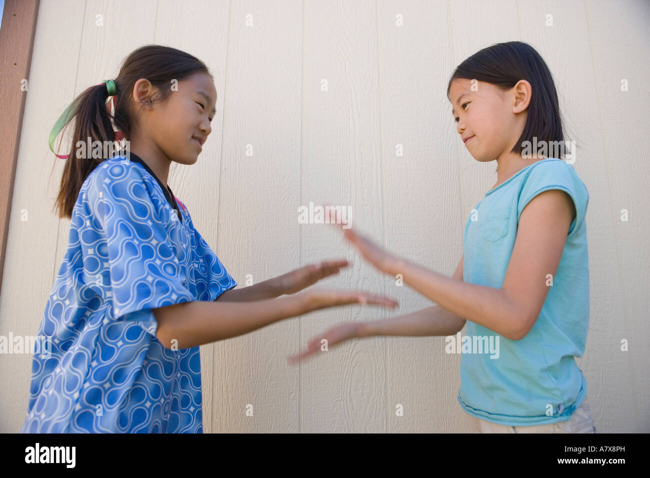 two chinese-american ten year old girls playing a hand clapping game ...