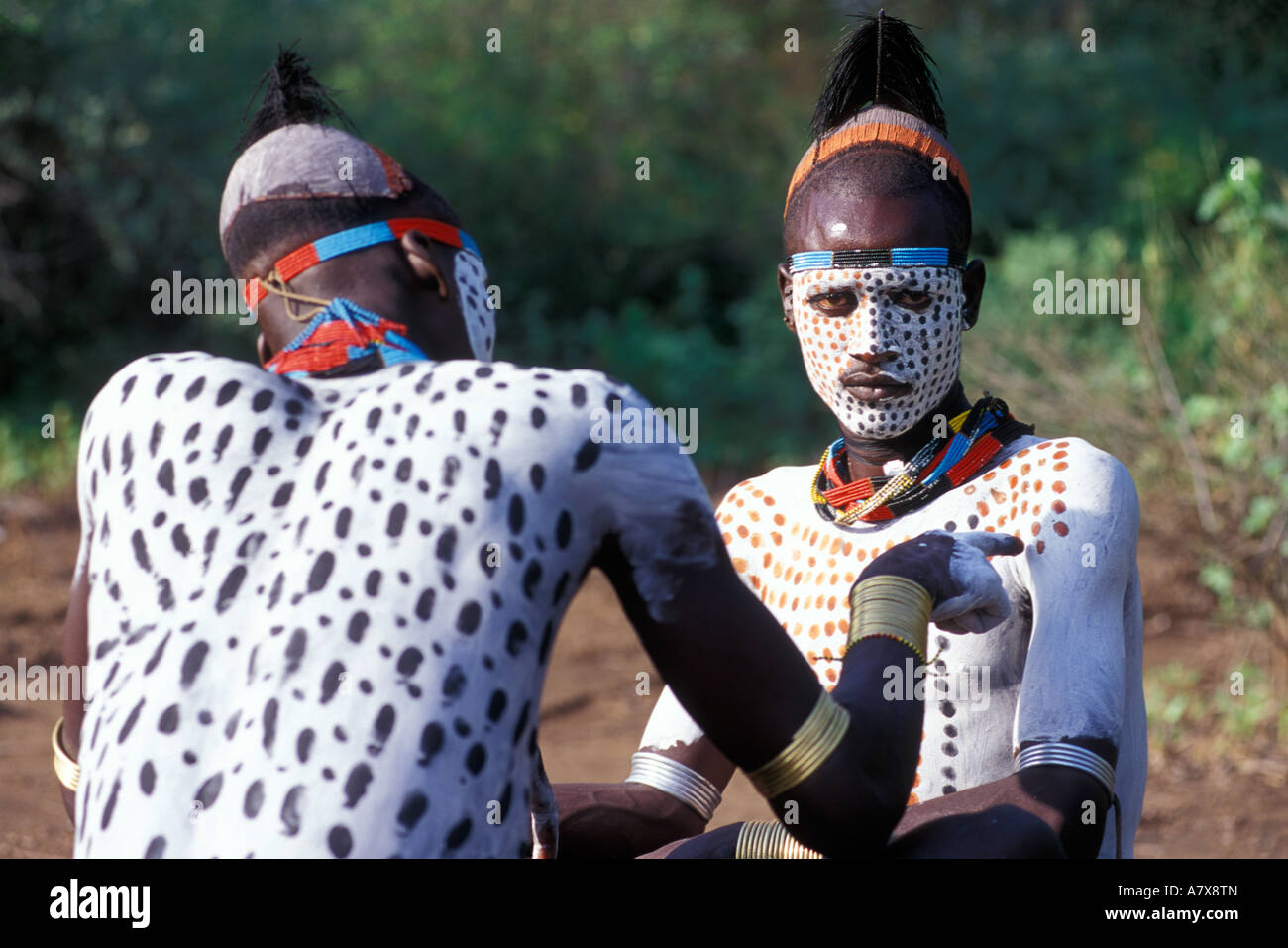 A Karo warrior puts body paint on another Karo man, in Ethiopia's Omo ...