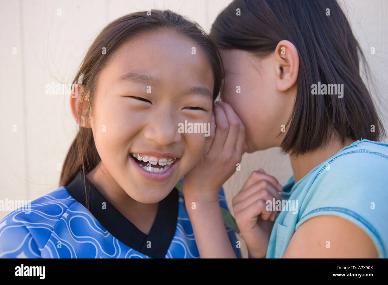 eight year old girl whispering a secret in friend's ear Stock Photo - Alamy